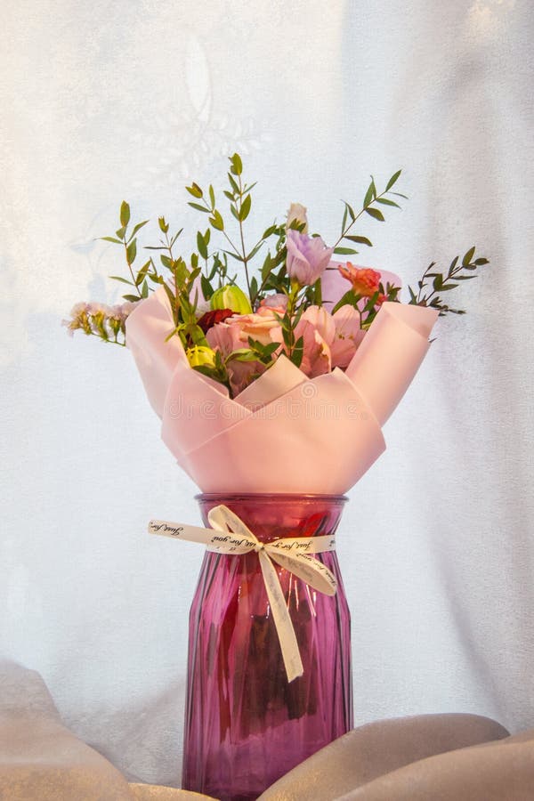 A Delicate Bouquet of Different Flowers in a Light Pink Wrapper Stands ...