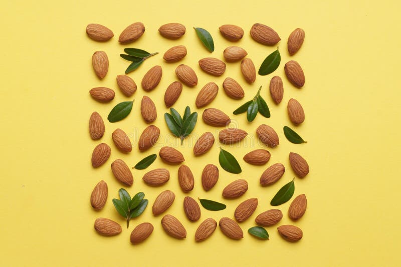 Delicious Almonds and Fresh Leaves on Yellow Background, Flat Lay Stock ...