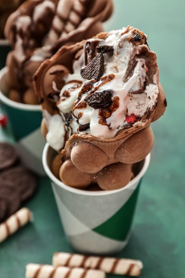 Delicious Bubble Waffles with Ice Cream in Cups on Color Table Stock ...
