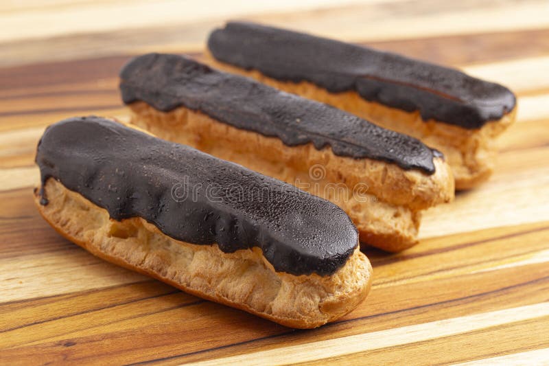 Delicious Cream Filled Chocolate Eclair Pastries on a Wooden Table ...