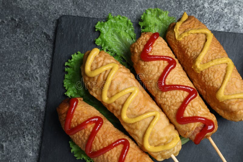 Delicious Deep Fried Corn Dogs with Lettuce and Sauces on Grey Table ...