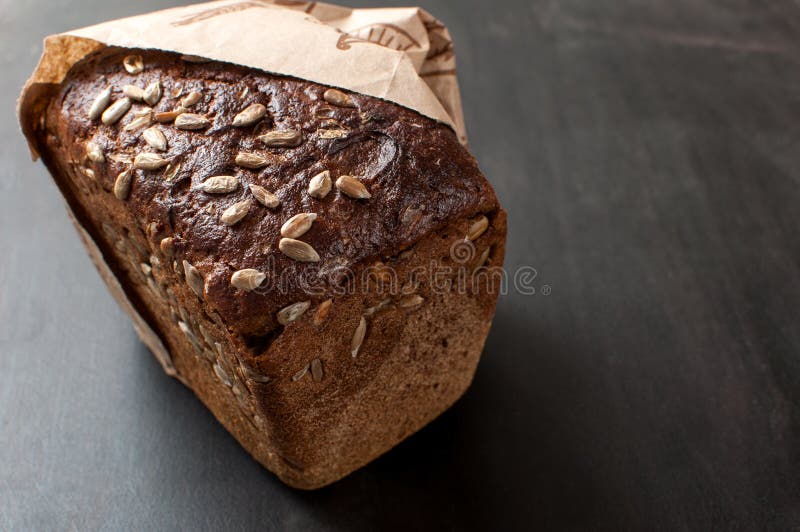Fresh Bread with Sunflower Seeds Bran in Paper Packaging on a Dark ...