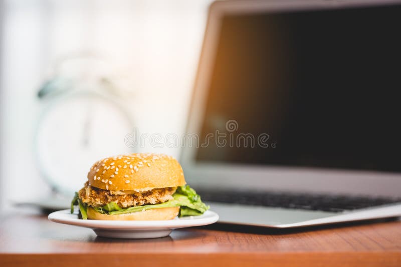 A Delicious Hamburger on the Table with a Blurred Computer Laptop and ...