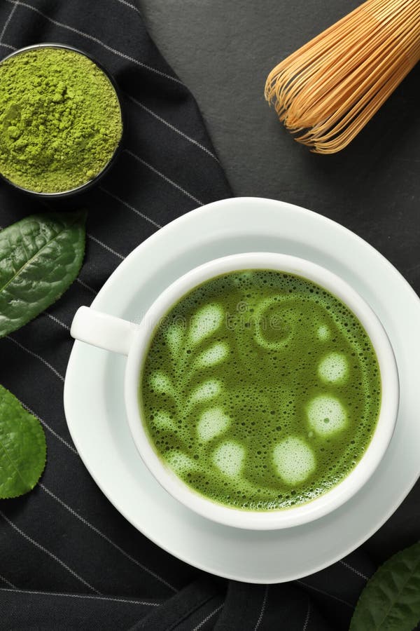 Delicious Matcha Latte, Powder, Leaves and Whisk on Dark Table, Flat ...