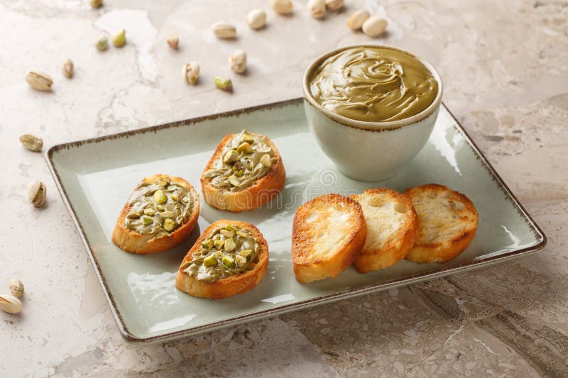 Delicious Pistachio Spread in Bowl, Toasted Bread and Raw Nuts Close-up ...