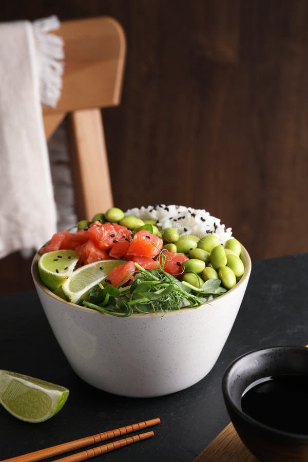 Delicious Poke Bowl with Lime, Fish and Edamame Beans on Black Table ...