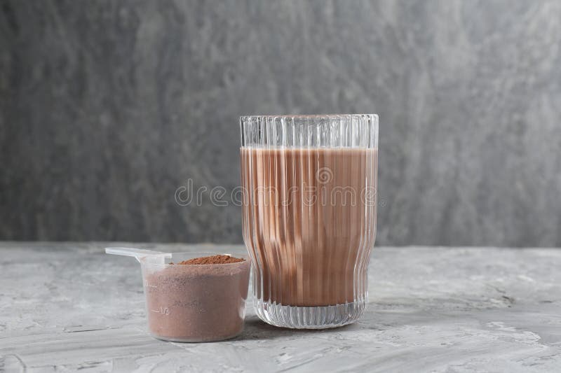 Delicious Protein Shake in Glass and Scoop with Powder on Grey Table ...