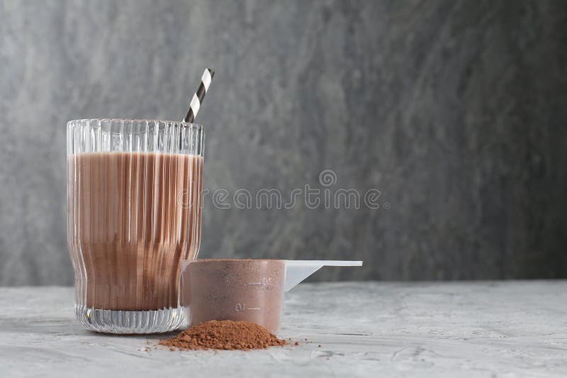 Delicious Protein Shake in Glass and Scoop with Powder on Grey Table ...