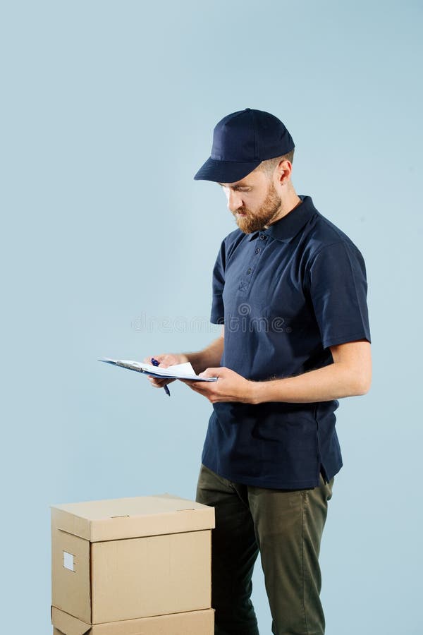 Delivery Man is Checking His Orders List while Standing Next To Stack ...
