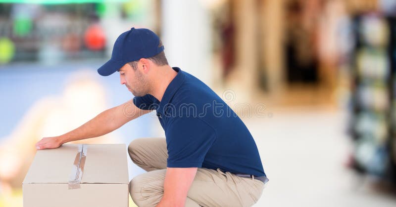 Delivery Man Picking Up Box Against Blurry Shopping Centre Stock Photo ...