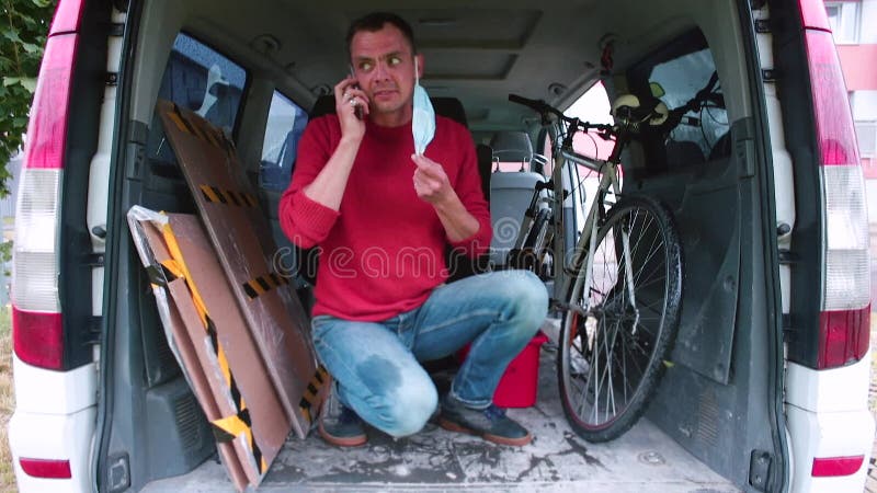 Delivery Man Talking Phone in Trunk of Car. he Puts Mask before ...