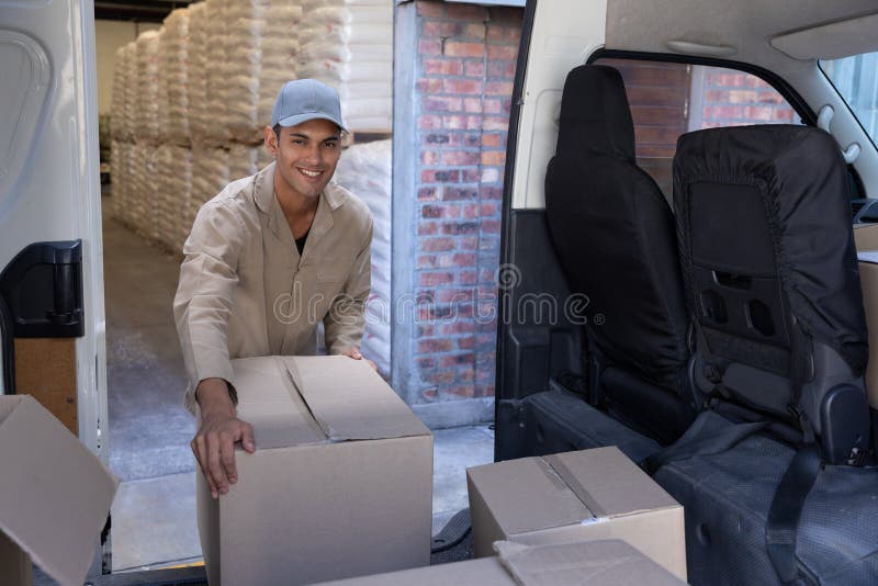 Delivery Man Unloading Cardboard Boxes from a Van Outside the Warehouse ...