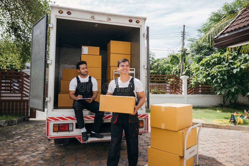 Delivery Men Unload Boxes from a Truck. Movers in Uniform Cooperate in ...