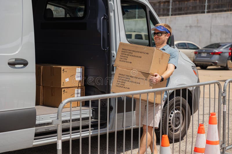 Delivery Worker Unloading Boxes from a Van in an Outdoor Parking Area ...