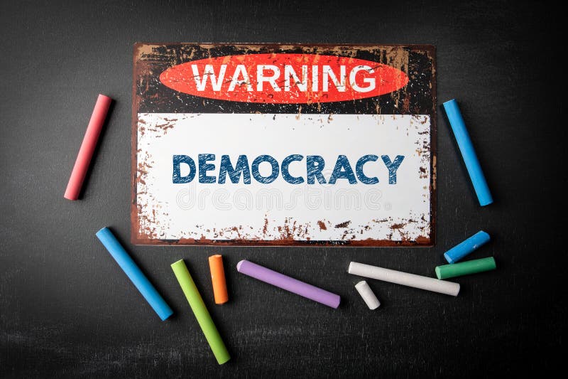 Democracy Concept. Metal Warning Sign and Colored Pieces of Chalk on a ... Democracy Concept. Metal Warning Sign and Colored Pieces of Chalk on a ...