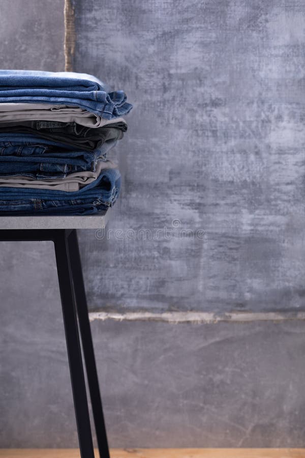 Denim Jeans at Shelf or Stool. Stack of Jeans Near Abstract Background ...