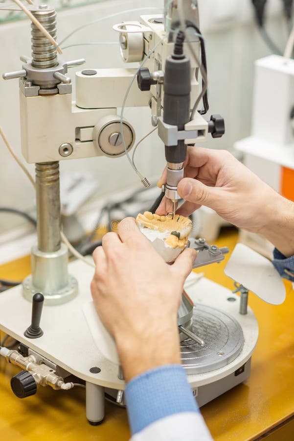 A Dental Technician Makes Partial Dentures on a Mechanized Machine. the ...