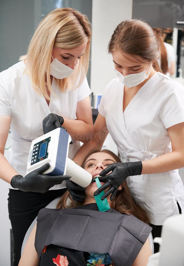 Dentist and Assistant Examining Patient Teeth with Dental X-ray Machine ...