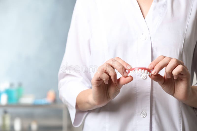 Dentist Holding Teeth Cover on Blurred Background, Closeup. Stock Photo ...