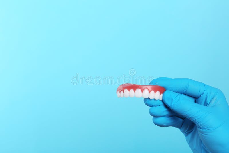 Dentist Holding Teeth Cover on Color Background. Stock Image - Image of ...