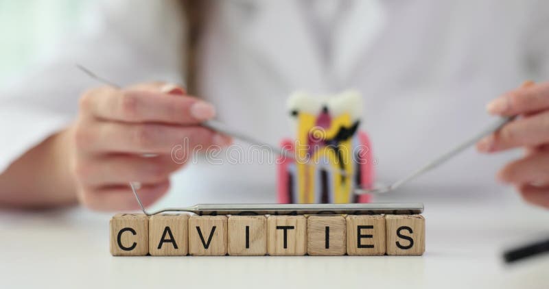 Dentist Shows an Artificial Tooth Model Over the Word Cavities Stock ...