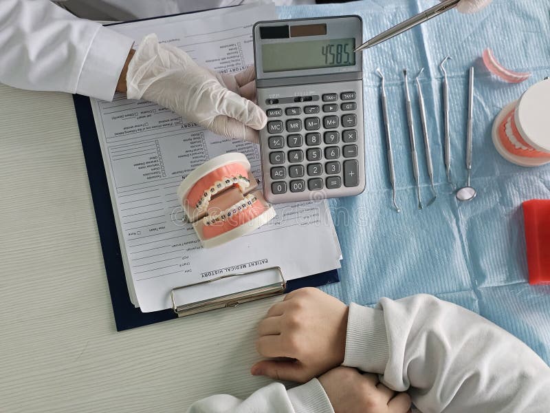 The Dentist Shows the Cost of Dental Braces on the Calculator Stock ...