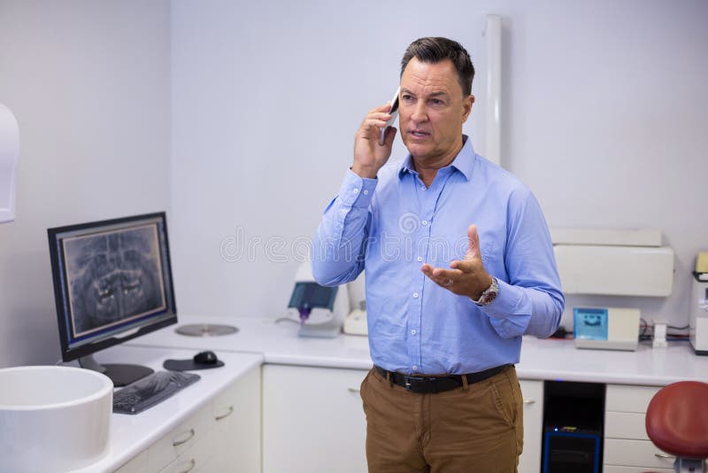 Dentist Talking on Mobile Phone Stock Image - Image of clinic ...