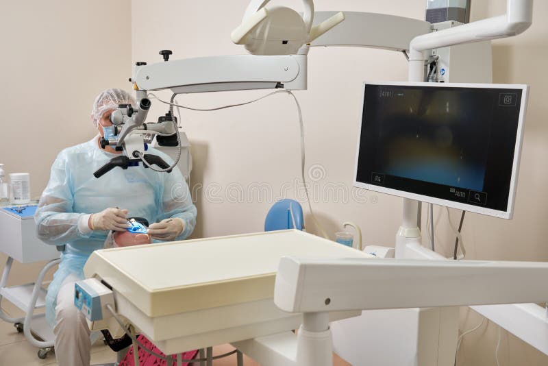 Dentist Working with Dental Microscope and Patient at Modern Dentist ...
