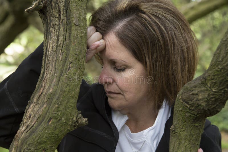 Depressed Middle Age Woman in Forest Leaning on a Tree Stock Image ...