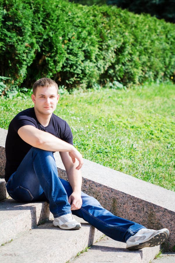 Der Junge Mann Sitzt Auf Einer Bank Stockfoto - Bild von erwachsener ...