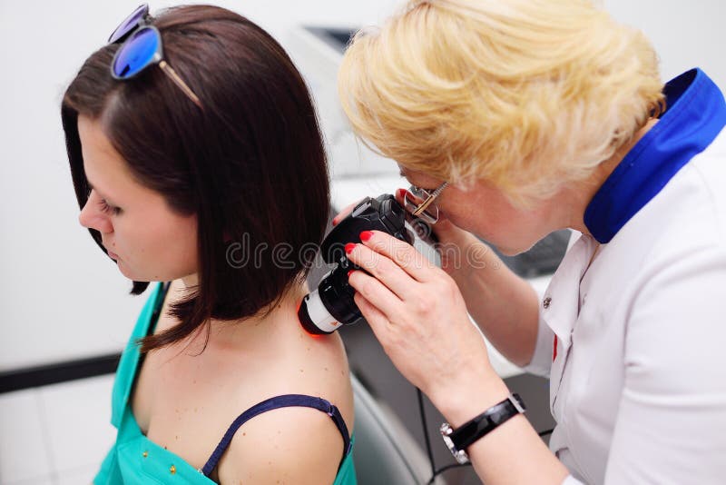 The Dermatologist Examines The Moles Or Acne Of The Patient With A