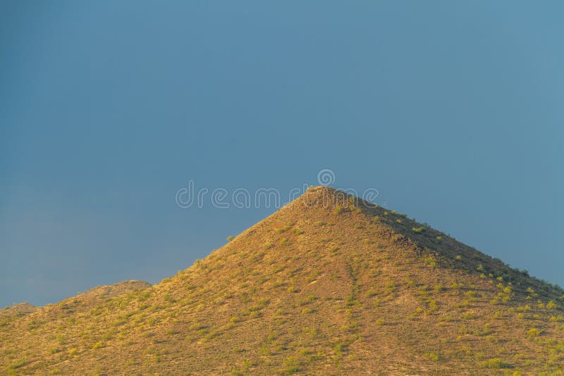 A Desert Mountain Lit by the Morning Sun with Dark, Ominous Clouds ...