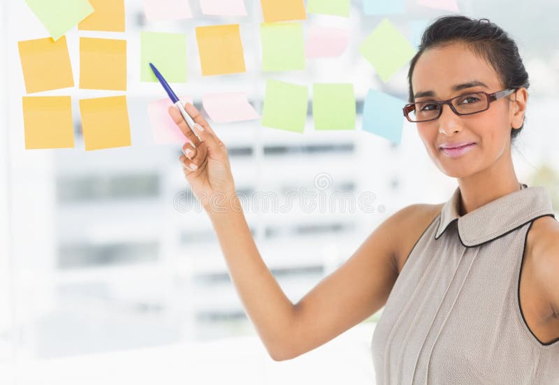 Designer Pointing To Sticky Notes on Window Smiling at Camera Stock ...