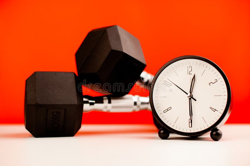 Clock on Desk Side by Side with Dumbbells for Exercise during Work Time ...