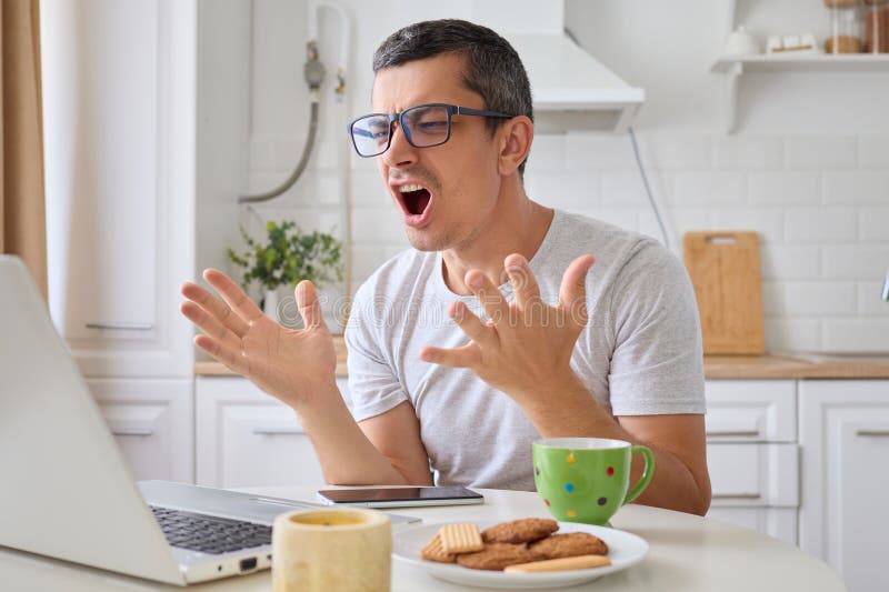 Despair Man Sitting at Table in Kitchen Working on Laptop Angrily ...