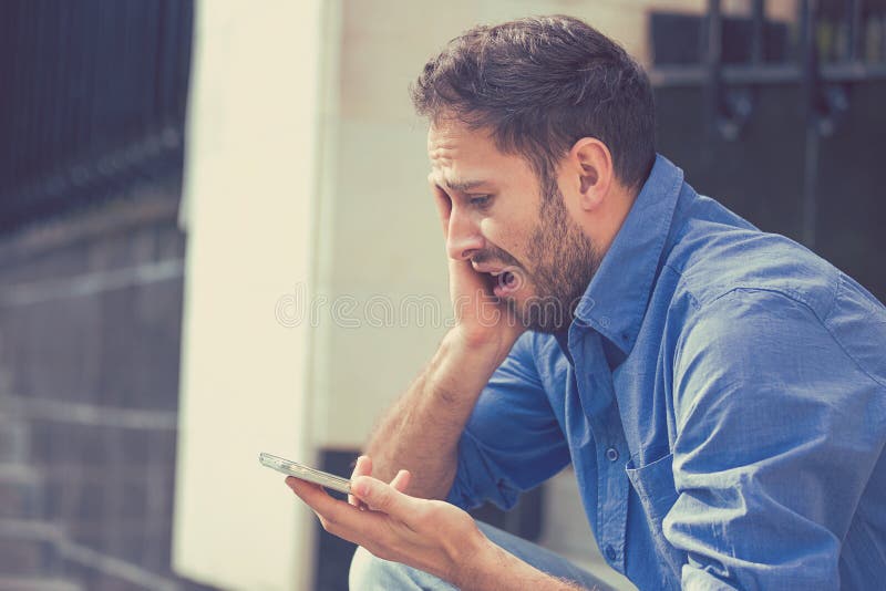 Desperate Sad Young Man Looking at Bad Text Message on His Mobile Phone ... Desperate Sad Young Man Looking at Bad Text Message on His Mobile Phone ...