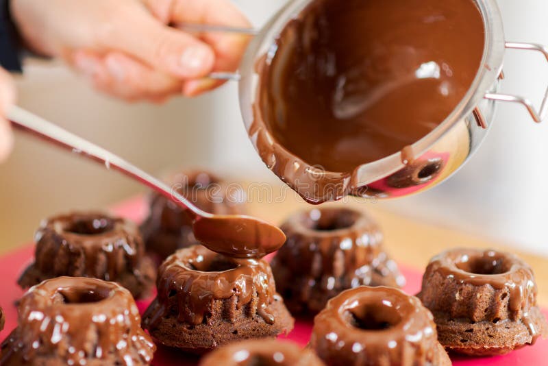 Detail of Chocolate Icing Being Applied on Top of Mini Ring Cakes on ...