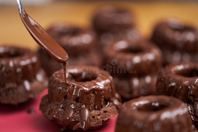 Detail of Chocolate Icing Being Applied on Top of Mini Ring Cakes on ...