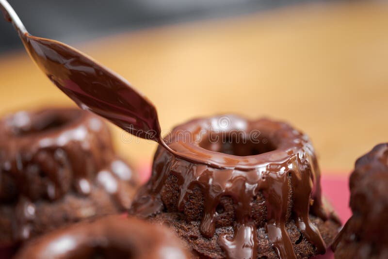 Detail of Chocolate Icing Being Applied on Top of Mini Ring Cakes on ...