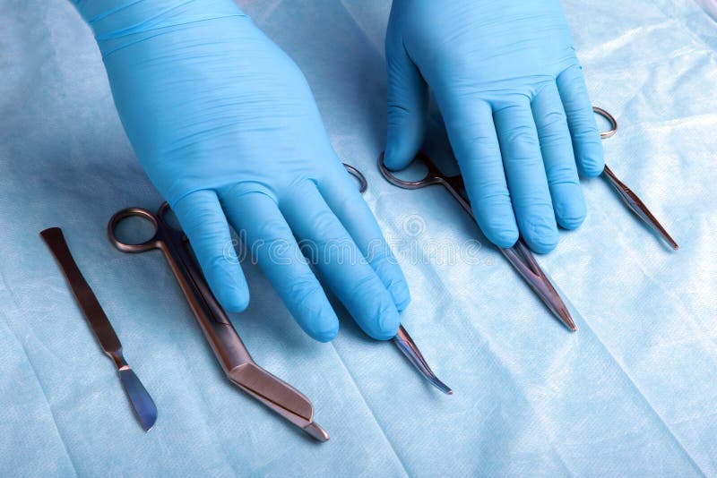 Detail Shot of Sterilized Surgery Instruments with a Hand Grabbing a ...