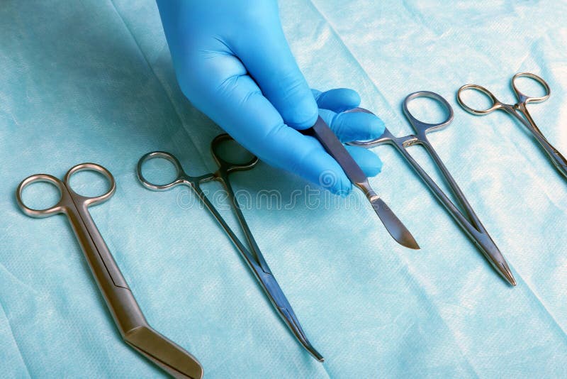 Detail Shot of Sterilized Surgery Instruments with a Hand Grabbing a ...