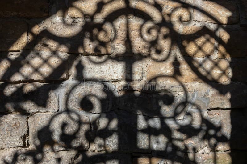 Intricate Shadows Cast by Wrought Iron Design on a Textured Stone Wall ...
