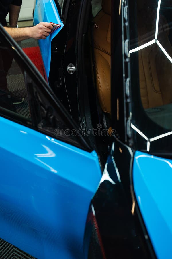 Detailing Expert Uses Red Squeegee Wrapper To Flatten Blue PPF Wrap on Car Surface. Vehicle Wrap ...