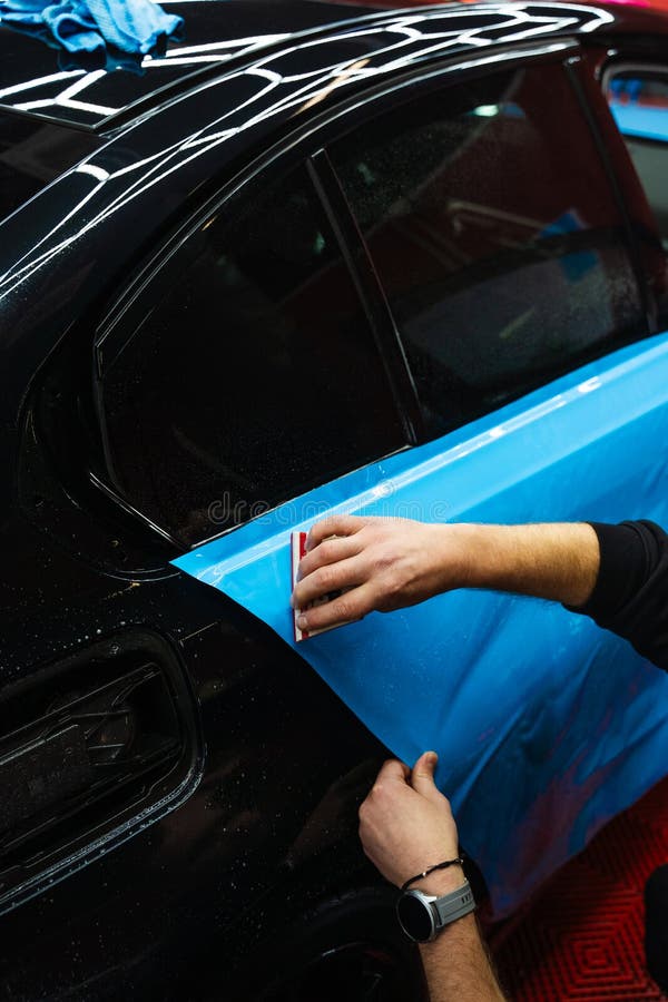 Detailing Expert Uses Red Squeegee Wrapper To Flatten Blue PPF Wrap on Car Surface. Vehicle Wrap ...