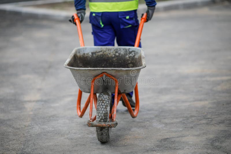 Details with a Construction Worker Pulling a Wheelbarrow on a ...