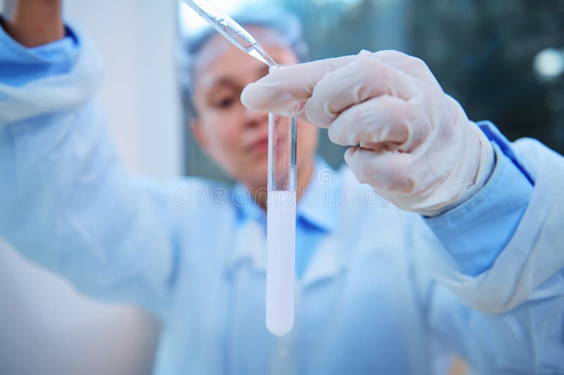 Hands of a Lab Assistant Dripping a Transparent Liquid from a Graduated ...