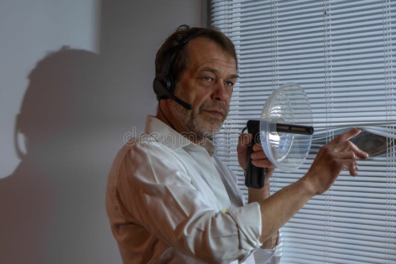 Detective on Assignment. a Man in a Headset Stands at a Window with ...
