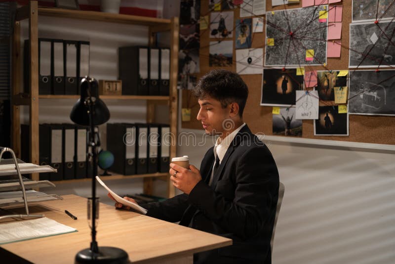 Detective Working at Desk in His Office, Drinking Coffee and Searching ...