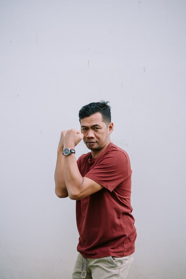 Determined Asian Man in Fighting Stance Against Plain Backdrop Posing ...