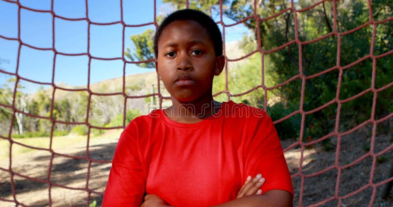 Determined Boy Standing with Arms Crossed Against Net during Obstacle ...